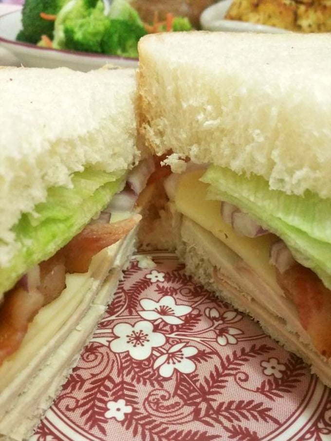 This sandwich isn't just stacked—it's architecturally sound. White bread, fresh veggies, and layers of deli meat creating the Taj Mahal of lunch.
