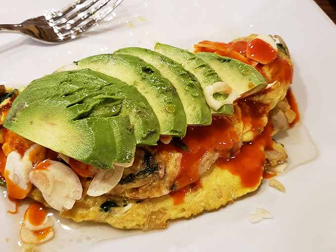 An omelet that's having an identity crisis as a work of art, complete with avocado crown. Michelangelo would've painted this if he'd been a chef.