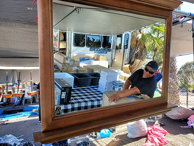 Every mirror at the swap meet tells a story—this one frames both merchandise and merchant in a perfect tableau of commerce and craftsmanship.