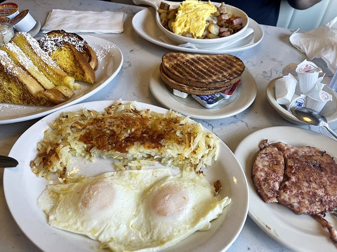 The breakfast spread that launched a thousand food dreams. Sunny-side eggs, perfectly crisped hash browns, and sausage links that snap with satisfaction.