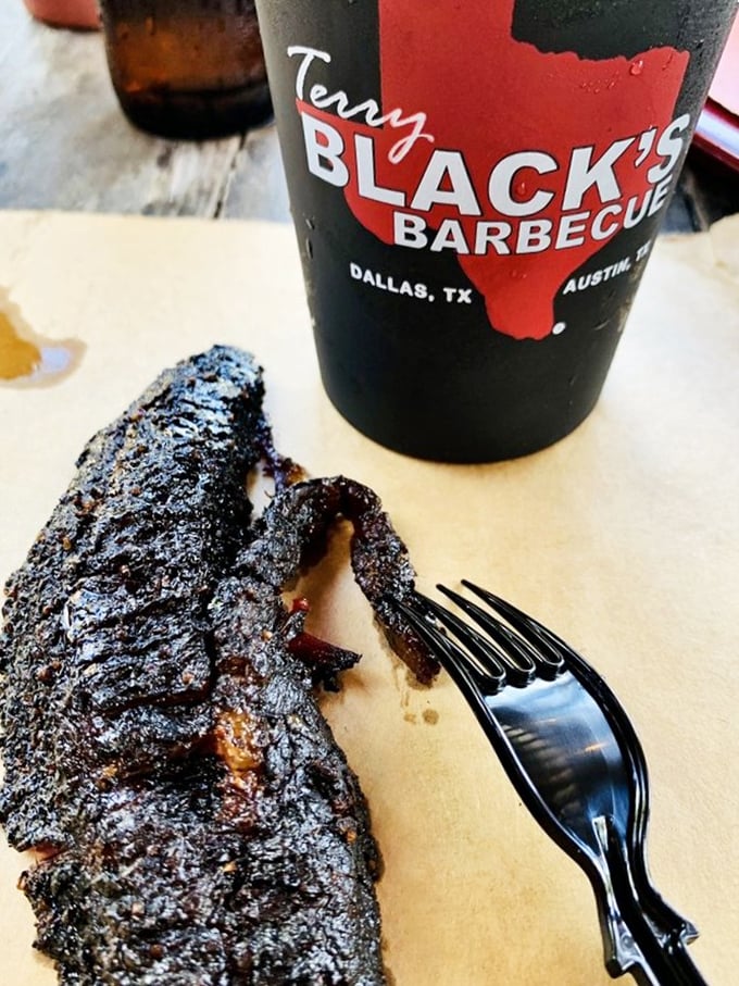 That cup isn't for drinking—it's holding Terry Black's burnt ends and a beverage that pairs perfectly with meat candy. Barbecue bliss in its purest form.