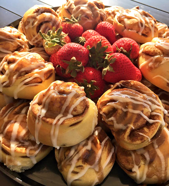 These cinnamon rolls aren't just baked, they're engineered for maximum pleasure—with strawberries playing the innocent bystander to all that glazed decadence.