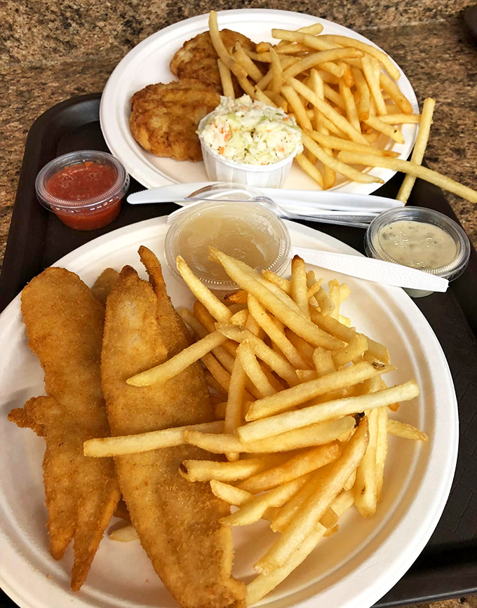 Two plates of seafood perfection—golden fish, crispy fries, and that essential cup of coleslaw. Comfort food that would make Poseidon himself come ashore for dinner.