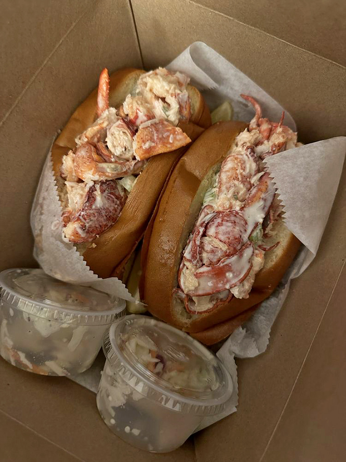 Behold the main event—lobster rolls so stuffed they're practically blushing, served with tiny cups of butter for those who believe too much is just right.