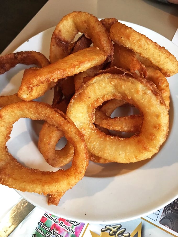 Onion rings with architectural integrity – crispy, golden halos that shatter satisfyingly with each bite while maintaining their perfect circular form.