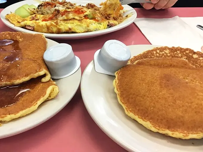 Pancakes so perfectly golden they deserve their own Instagram account, flanked by syrup vessels standing at attention.