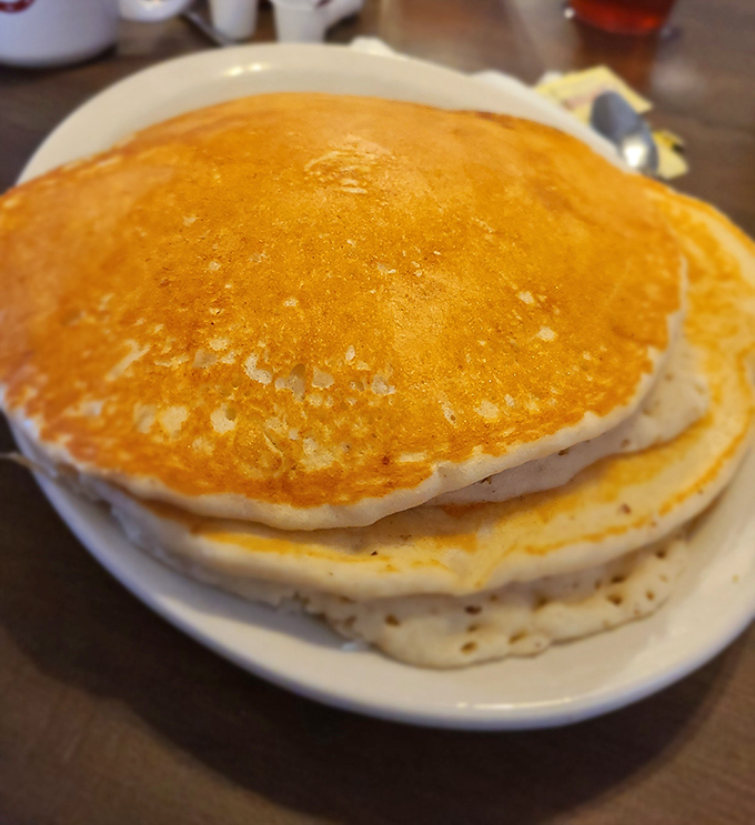 Pancakes so fluffy they could double as pillows – golden discs of breakfast perfection just waiting for their maple syrup waterfall moment.