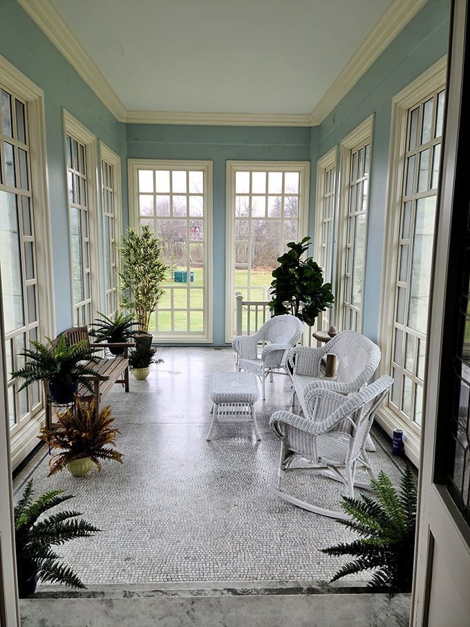 The sunroom's wicker furniture and wall-to-wall windows create the perfect spot for morning coffee or plotting your next industrial empire—your choice. 