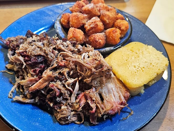 Pulled pork that's had a proper introduction to smoke and patience. Those sweet hush puppies aren't just sides—they're essential supporting characters in this delicious story.