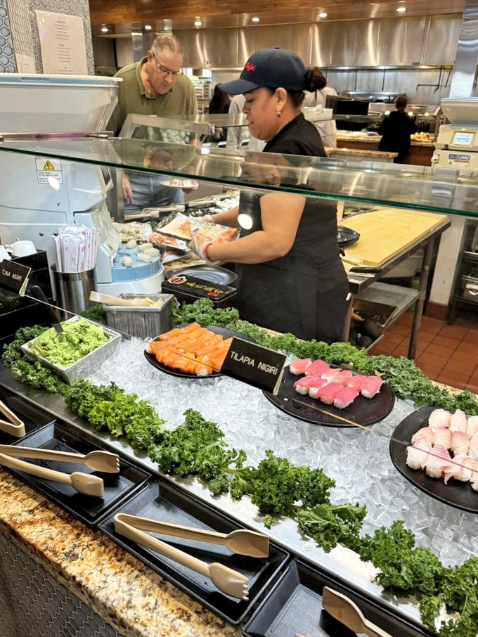 At the sushi station, fresh nigiri awaits while a skilled chef prepares the next batch – a delicious assembly line of oceanic delights.