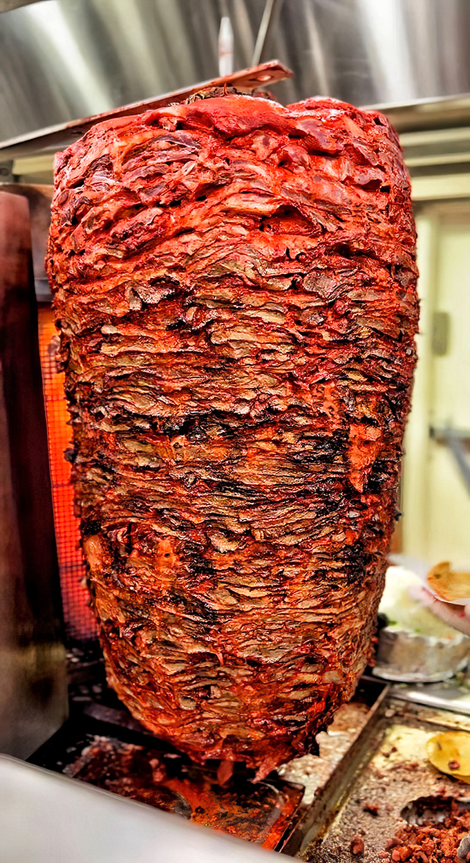 The trompo spins like a delicious disco ball, creating layers of flavor through ancient culinary magic.