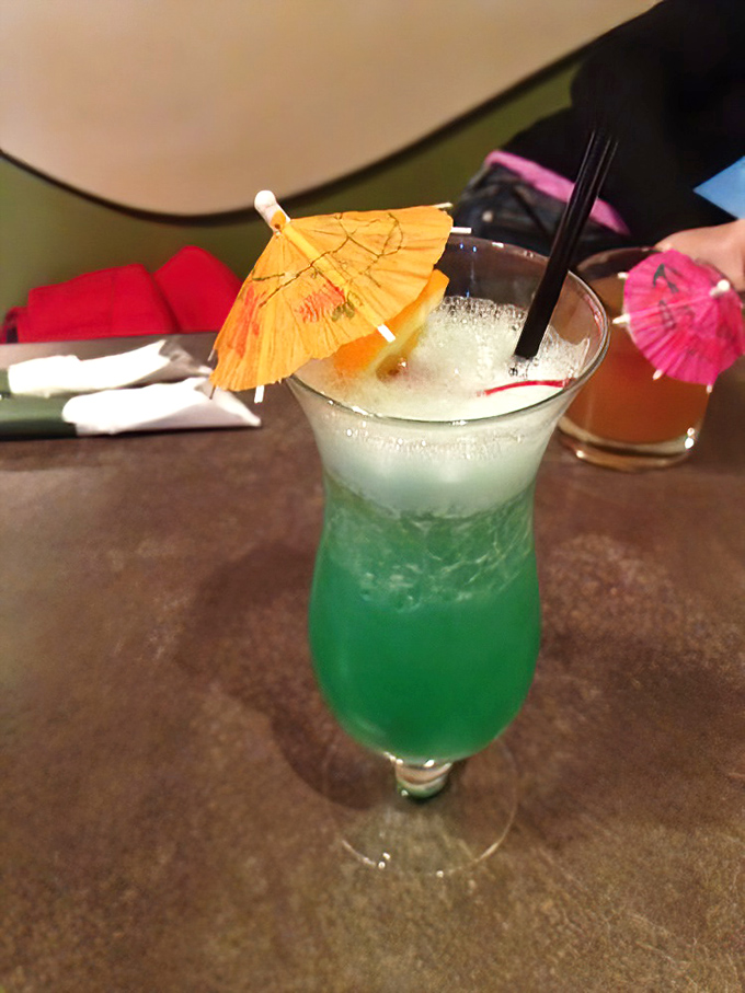 Vacation in a glass! This vibrant blue-green cocktail topped with playful paper umbrellas brings tropical vibes to the Midwest – no passport required.