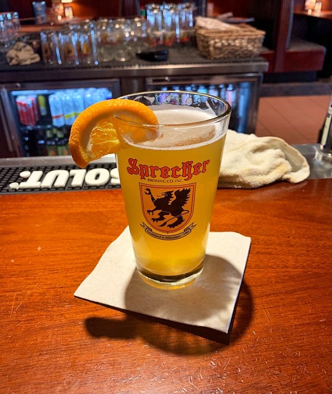 A perfectly poured Sprecher with an orange slice – because in Wisconsin, beer is both art form and necessary food group.