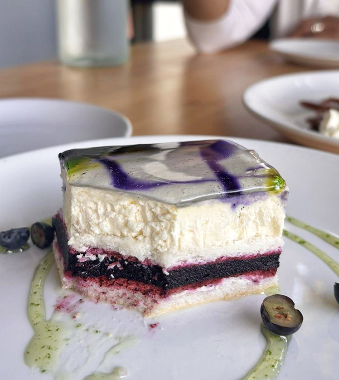 Dessert architecture at its finest—layers of berry-infused cake beneath a silky white topping, finished with an artistic gel that's almost too beautiful to eat. Almost.