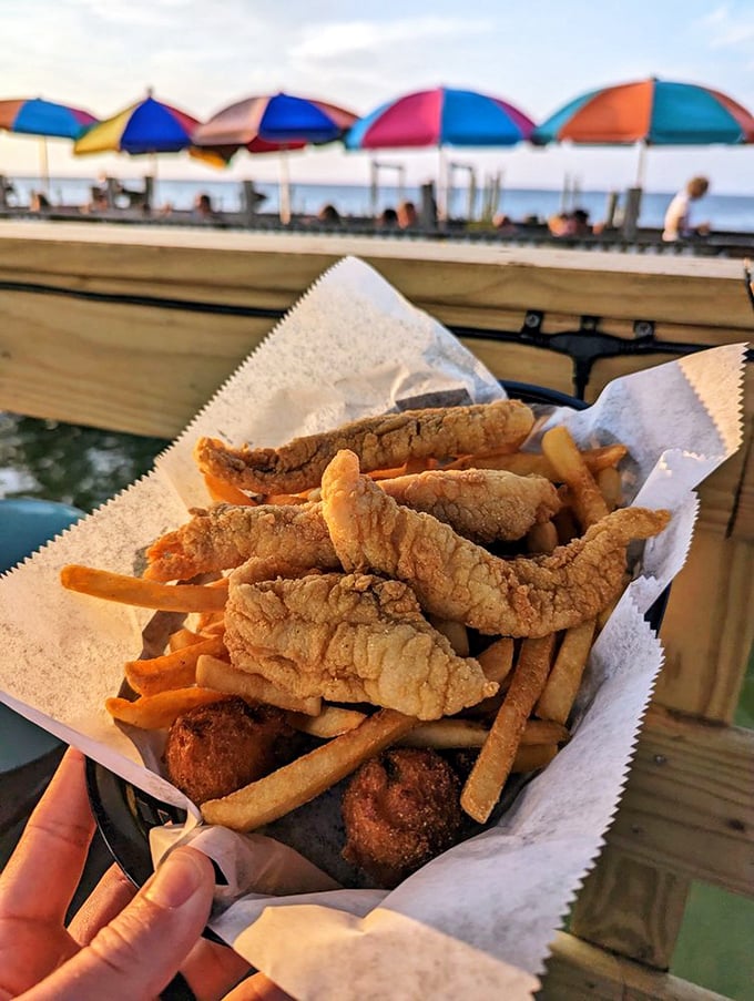 Waterfront dining done right – crispy fish strips and fries in a paper-lined basket that somehow taste better with your toes near the tide.