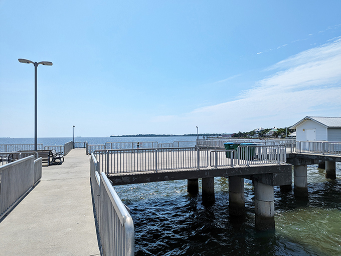 The concrete pier beckons anglers and dreamers alike to cast their hopes into blue-green waters.