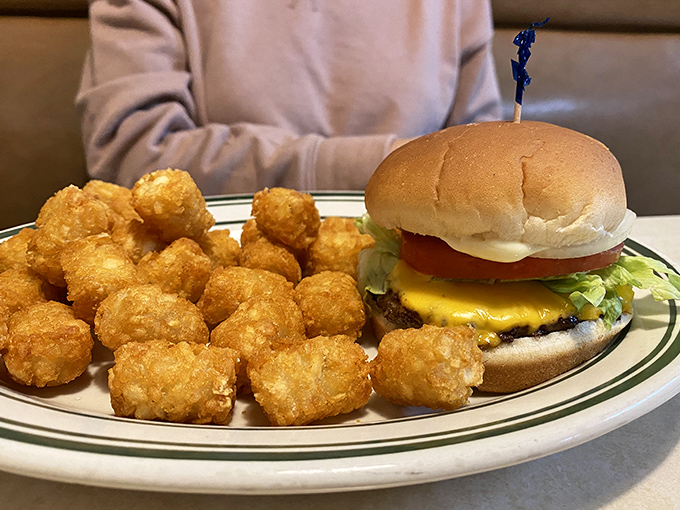Golden tater tots surround a cheeseburger that understands the assignment – comfort food at its finest.