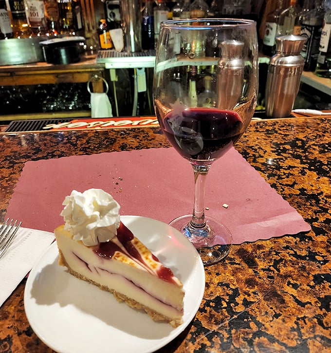 A slice of berry-swirled cheesecake paired with red wine – because sometimes dessert isn't just a course, it's a life philosophy.