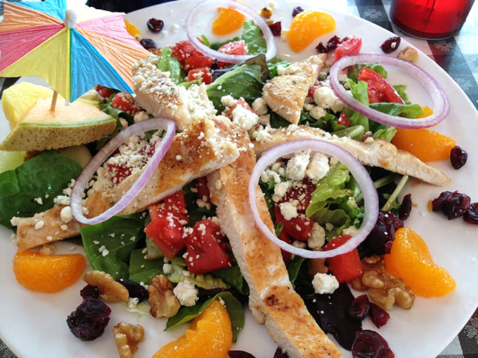 A salad that doesn't apologize for being healthy—crisp greens, feta, mandarin oranges, and grilled chicken under a colorful umbrella.