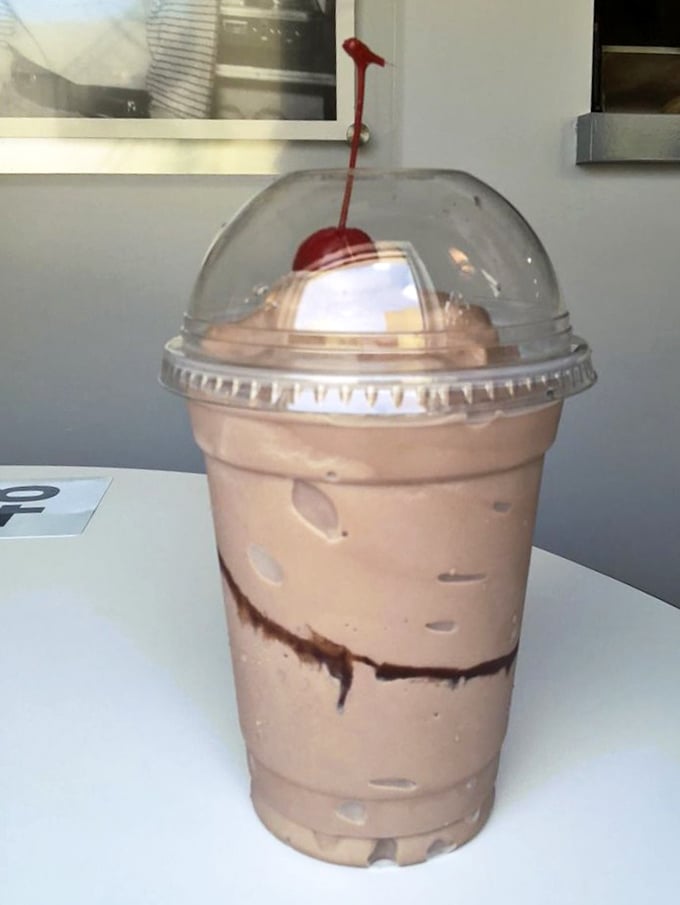 The chocolate milkshake comes crowned with a cherry, thick enough to require a spoon first—dessert masquerading as a beverage.
