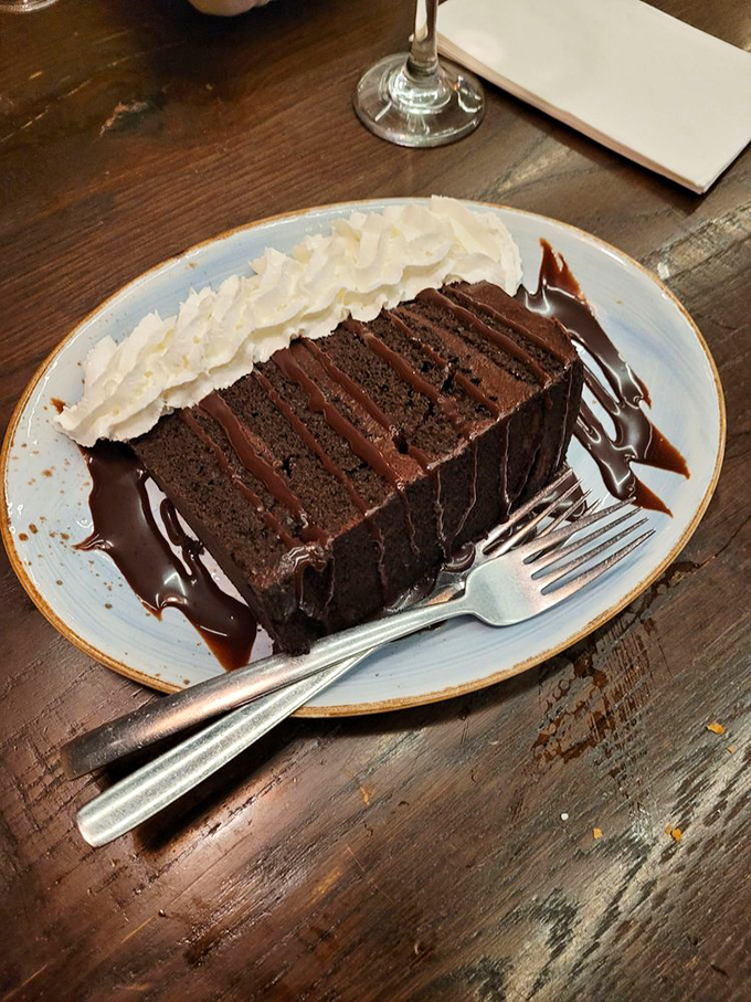 A chocolate cake so rich it probably has its own accountant. That whipped cream isn't decoration—it's necessary balance in an indulgent universe. 