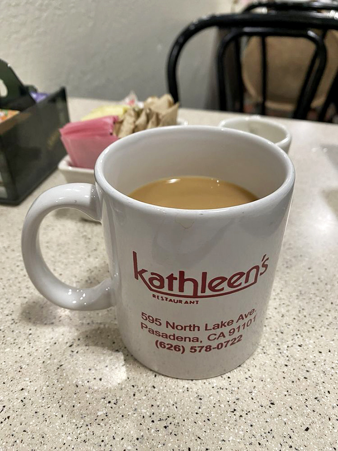 The official morning kickstart—Kathleen's branded mug promises the caffeinated courage needed to face whatever Monday throws your way.