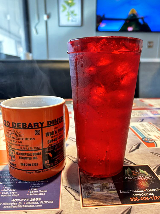 Coffee and Water: The diner's power couple—a sturdy orange mug of coffee alongside crimson-hued refreshment, served atop a tabletop collage of local business cards.