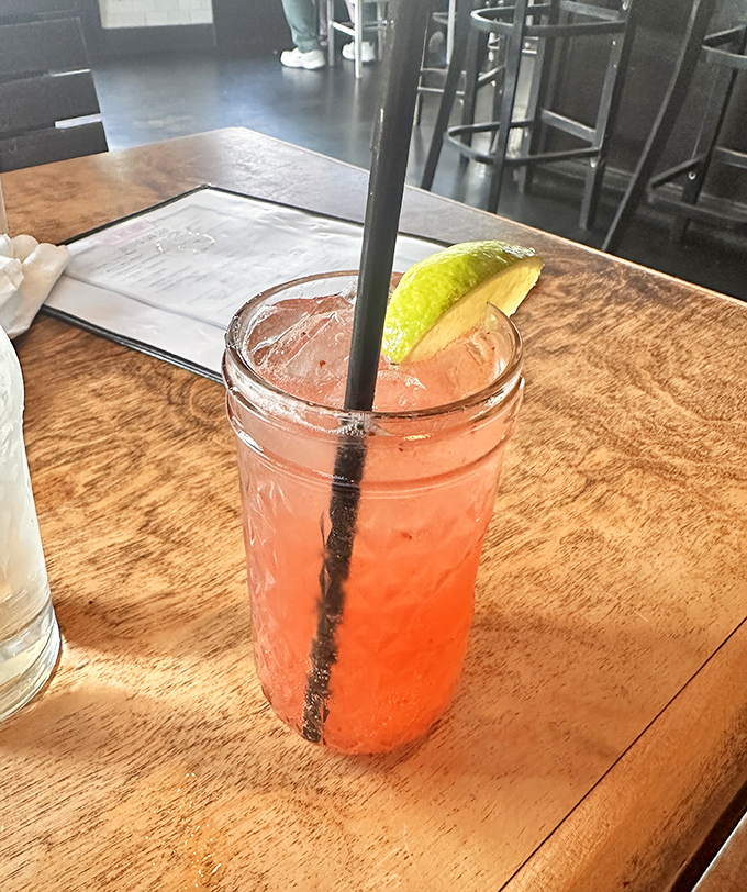 This isn't just a cocktail—it's liquid sunshine in a mason jar, complete with a lime wedge perched on the rim like it owns the place.