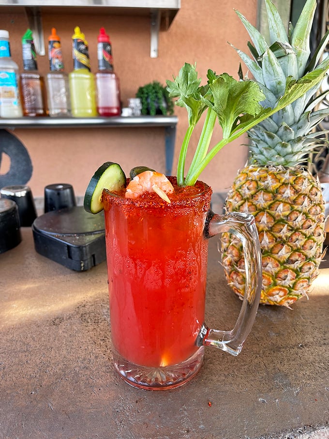 This isn't just a michelada – it's summer in a glass, with its spicy rim, fresh garnishes, and that perfect crimson hue promising refreshment.