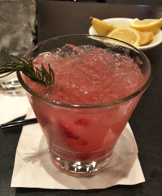 A ruby-red cocktail garnished with rosemary—like a little Christmas tree in your glass. Proof that serious drinks can still have a playful spirit.