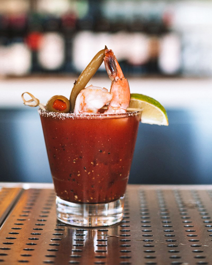 The Fisherman's Mary doesn't just have a shrimp garnish—it has an entire ocean adventure perched on its salt-rimmed edge.