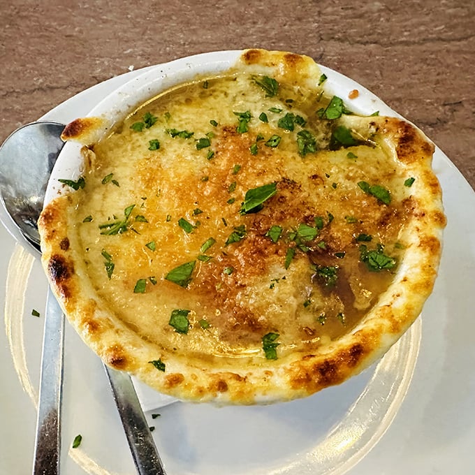 Bubbling cheese ceiling meets savory soup basement. This French onion soup isn't just comfort food—it's a warm hug in a crock.