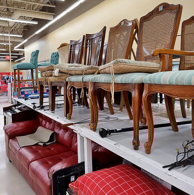 Dining chairs perch above a red leather sofa like aristocrats surveying the commoners—furniture with stories just waiting to be adopted.