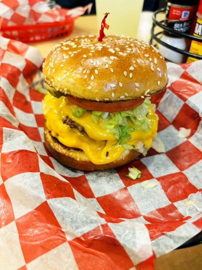 Cheese cascading like a yellow waterfall over fresh lettuce and tomato. This towering creation demands both hands and your complete attention—conversation can wait.