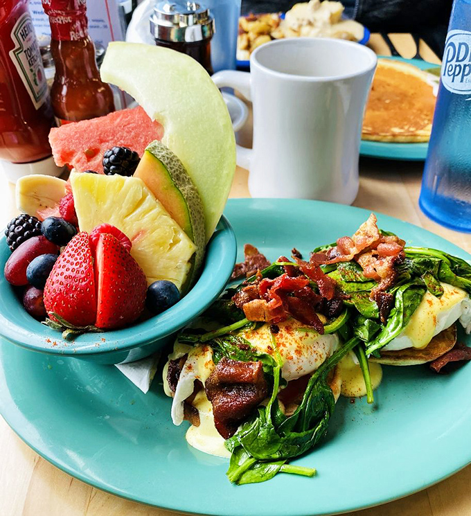 Breakfast nirvana: eggs Benedict with a side of fresh fruit that looks like it was arranged by someone who actually cares about your day.
