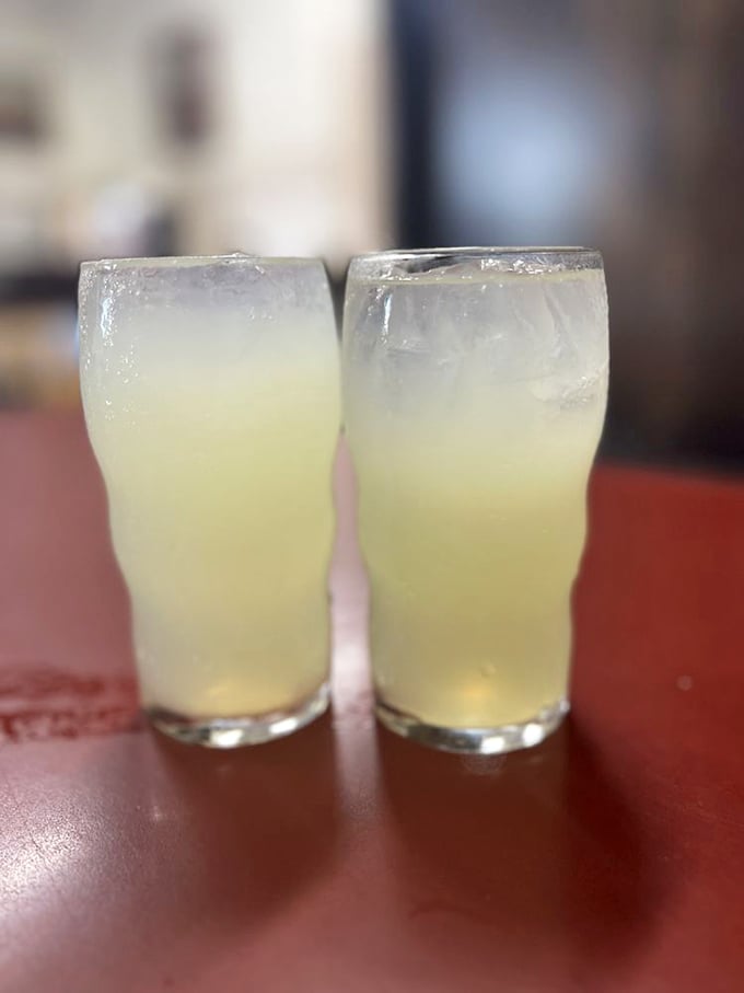 Two glasses of lemonade sitting pretty on the red tabletop—the perfect sweet-tart counterpoint to the savory sandwich experience.