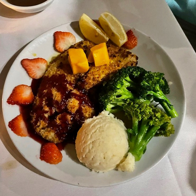 This isn't just fish—it's a tropical vacation on a plate. Mango-topped macadamia-crusted mahi with sides that know their role in this delicious ensemble.