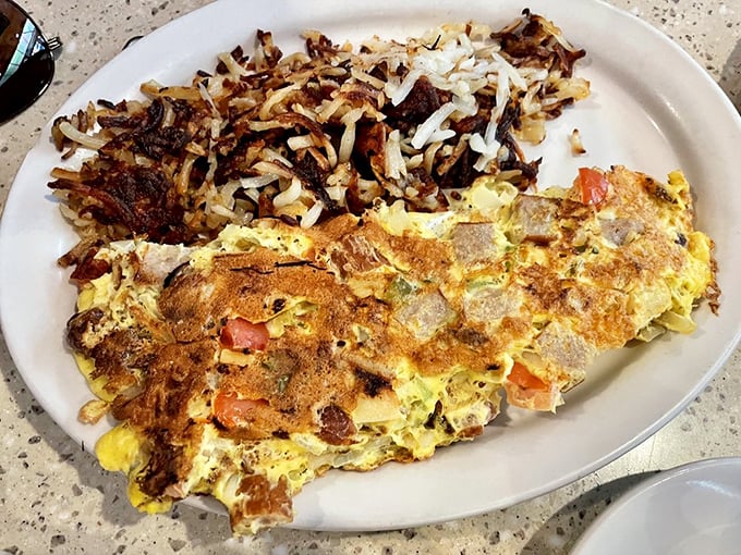 This isn't just an omelet—it's an architectural masterpiece with crispy hash browns as its foundation.