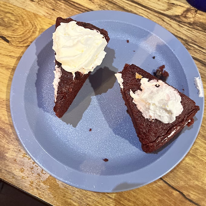 Red velvet cake so moist it should require a lifeguard. That whipped cream isn't just a topping—it's the cloud this dessert deserves to float on.