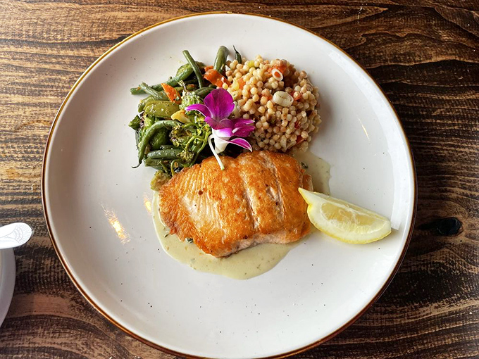 Simple perfection on a plate—crisp-skinned salmon, vibrant vegetables, and pearl couscous. The kind of dish that makes you wonder why you'd ever order anything else.