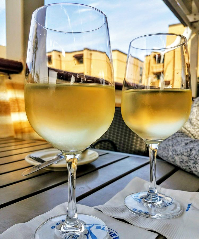 Two glasses of crisp Sauvignon Blanc catching the golden hour light—because seafood without wine is like a day without sunshine.