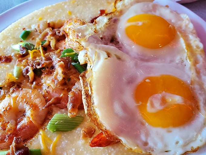 Two sunny eggs keeping watch over a landscape of creamy grits and succulent shrimp—a Southern breakfast masterpiece that belongs in the Louvre.