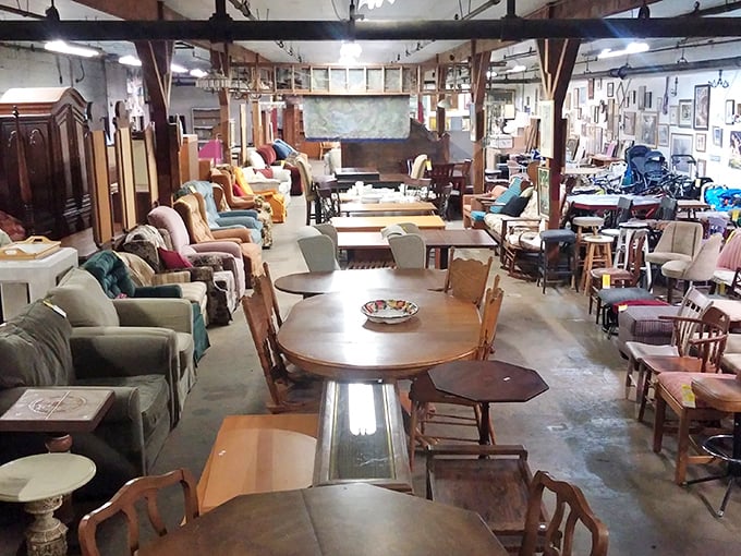 Tables and chairs arranged like a furniture forest, each piece with its own personality just waiting for the right home to adopt it.
