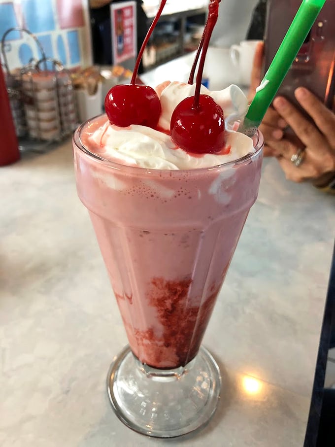 The strawberry milkshake arrives like a pink cloud topped with whipped cream and cherries – childhood nostalgia in a glass, but better than you remember.