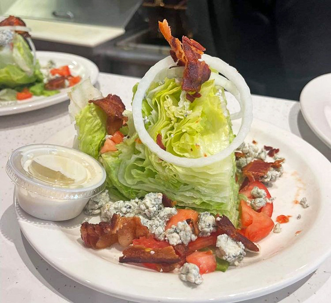 A wedge salad that makes eating vegetables feel like cheating. That ring of onion standing guard over blue cheese and bacon is architectural genius.