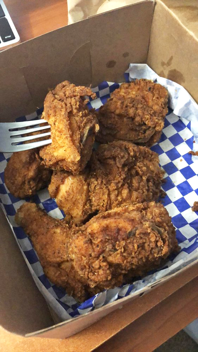 Fried chicken in its natural habitat—a cardboard box lined with checkered paper. No pretense, just pieces of perfection waiting to change your definition of comfort food.