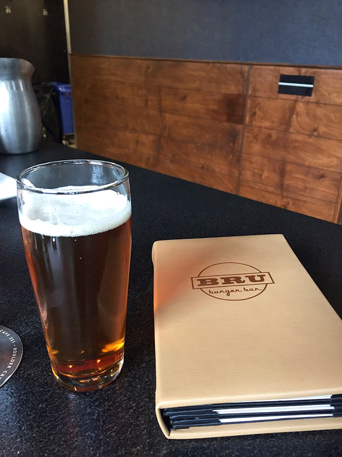 A perfectly poured craft beer alongside the leather-bound menu—a pairing as classic as Bogart and Bacall.