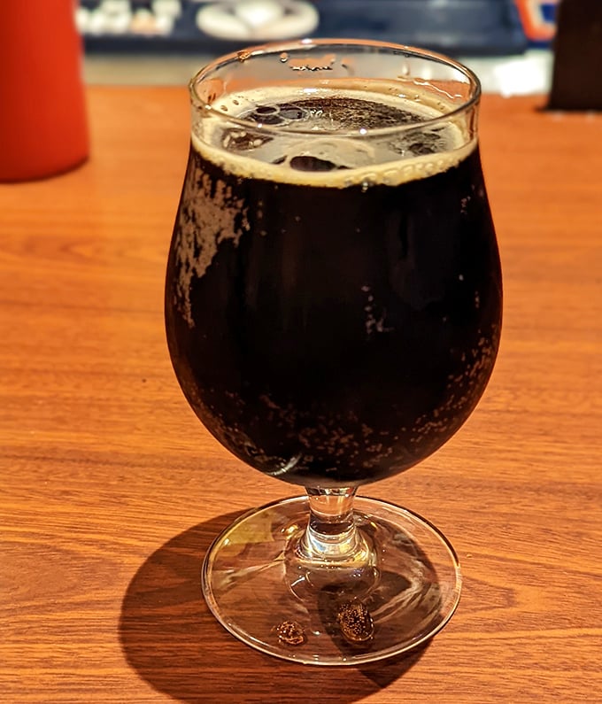 A dark, rich craft beer in proper glassware—because even when eating hot dogs, we deserve a touch of civilization.