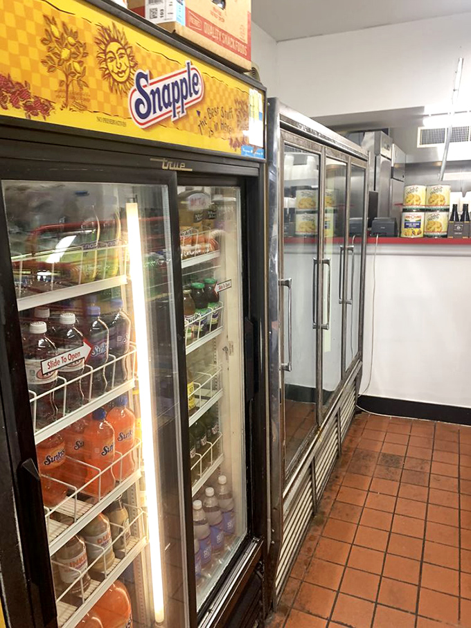 The beverage cooler—where every Snapple bottle waits for its destiny as the perfect hoagie companion. Hydration is serious business here.