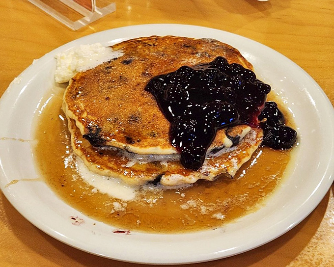 Blueberry pancakes swimming in syrup and topped with fruit compote – breakfast elevated from mere sustenance to morning celebration.